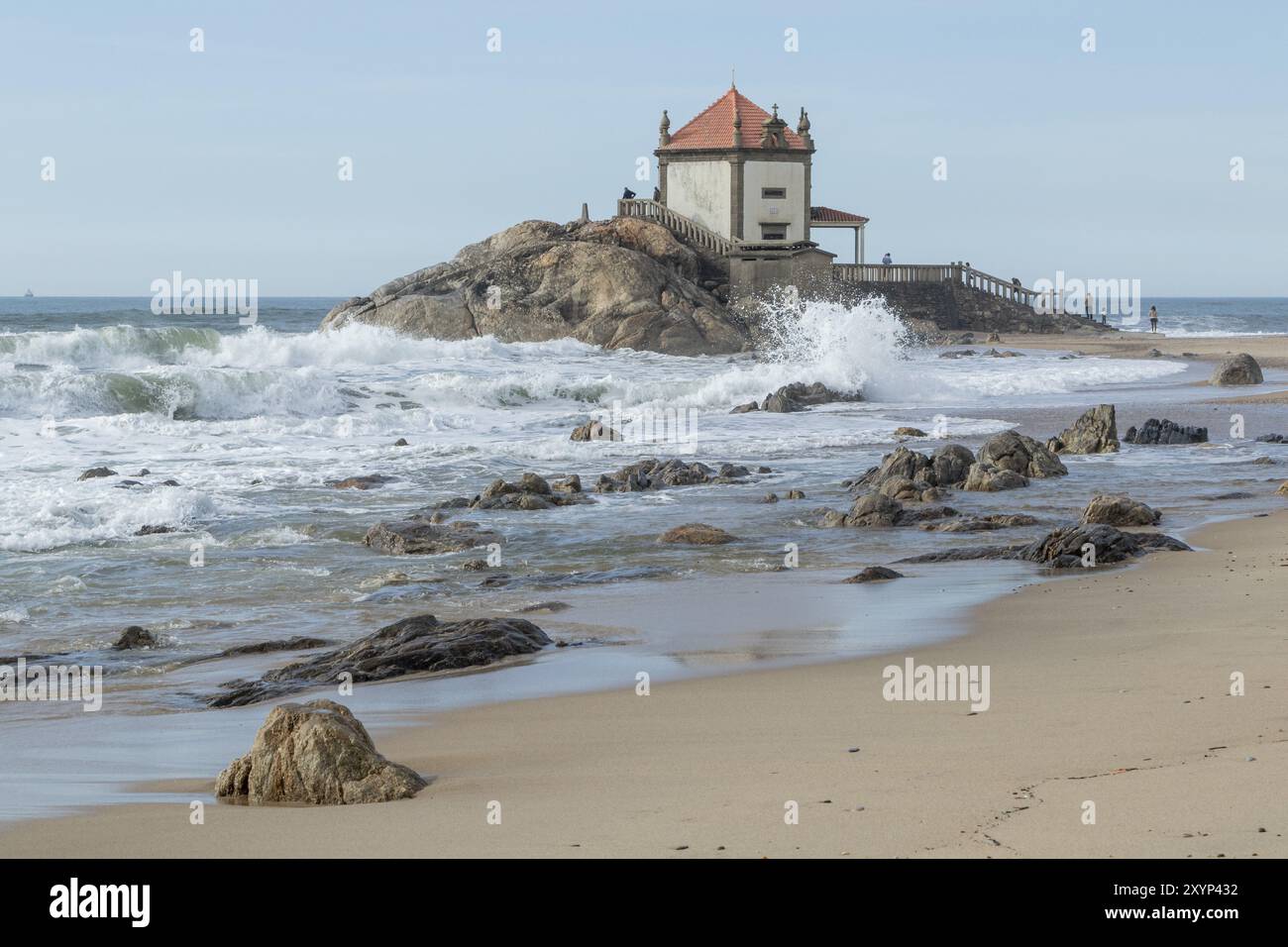 Waves, surf, sandy beach and landmark Capela do Senhor da Pedra ...