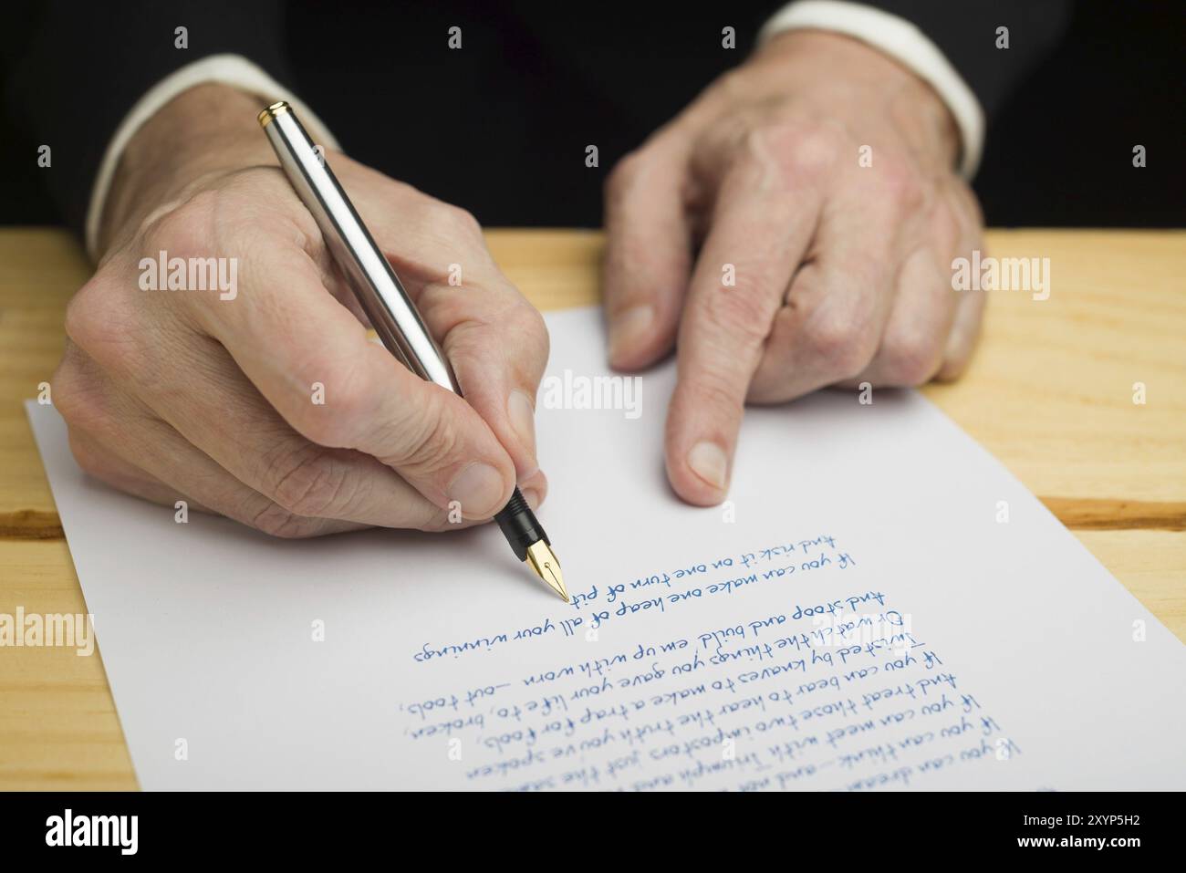 A businessman writing with a fountain pen on a white paper set on a ...