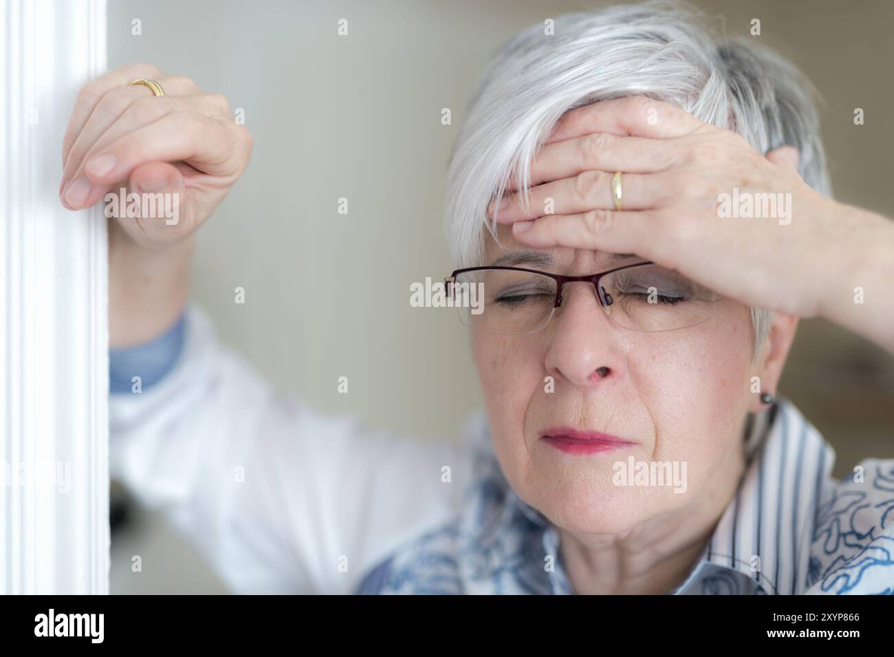 An elderly lady with a headache holds her hand to her forehead Stock ...