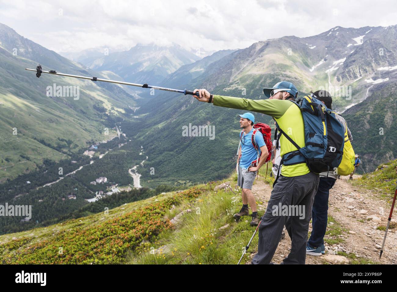 A group of hiker tourists with backpacks and tracking sticks rest and ...