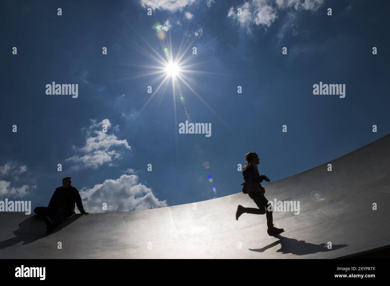 A girl walks in the backlight of the sun on a curved steel plate Stock ...
