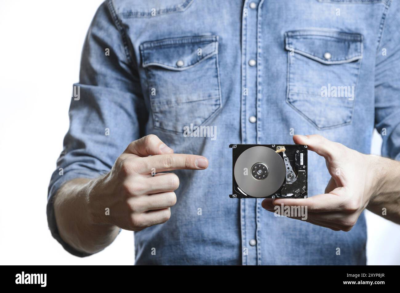 Man's hand holds a 2.5 inch hard drive. He's points to the hard disk ...