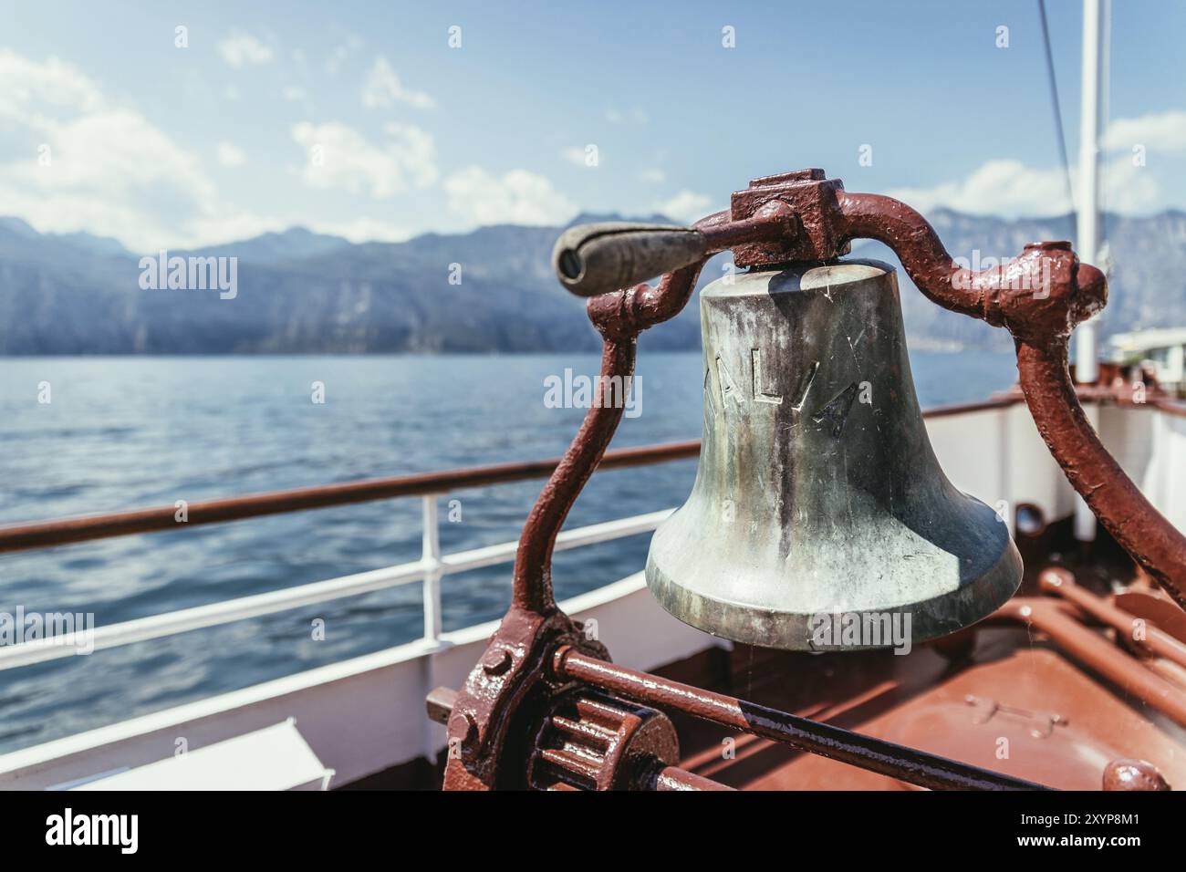 Bow of a boat with boat bell on a cruise tour. Blue water, mountain ...
