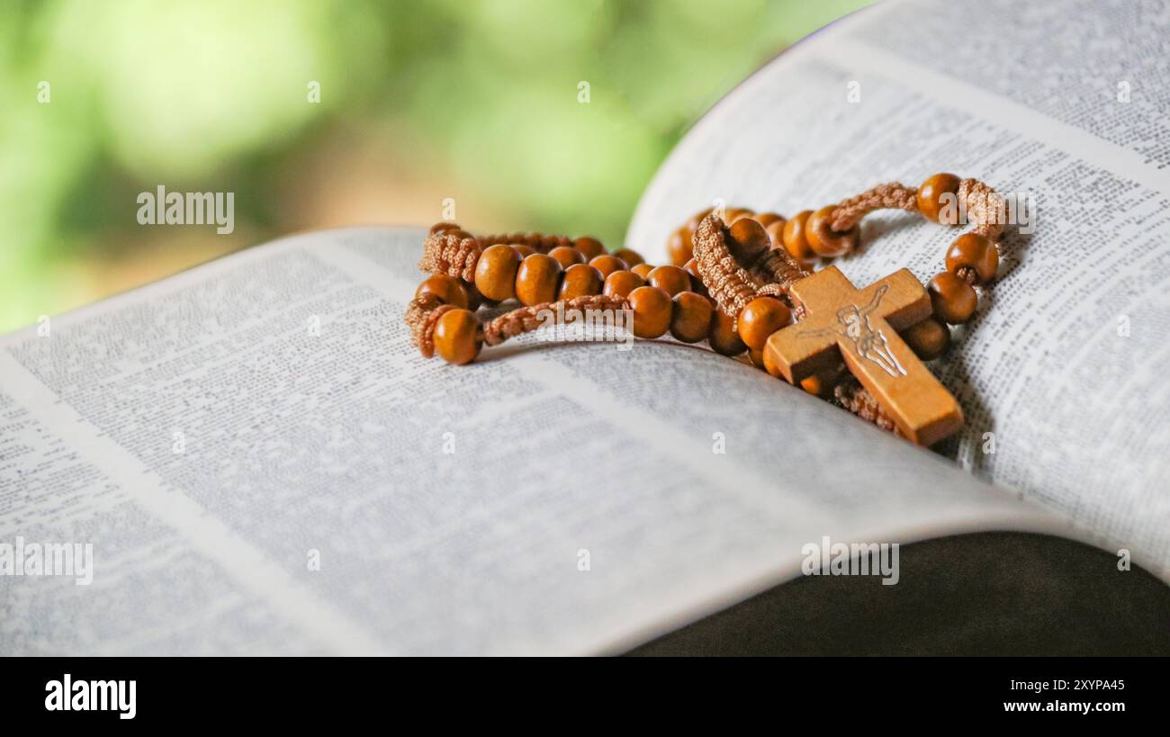 Dark brown wooden cross on an old open book symbolizing the spread of ...