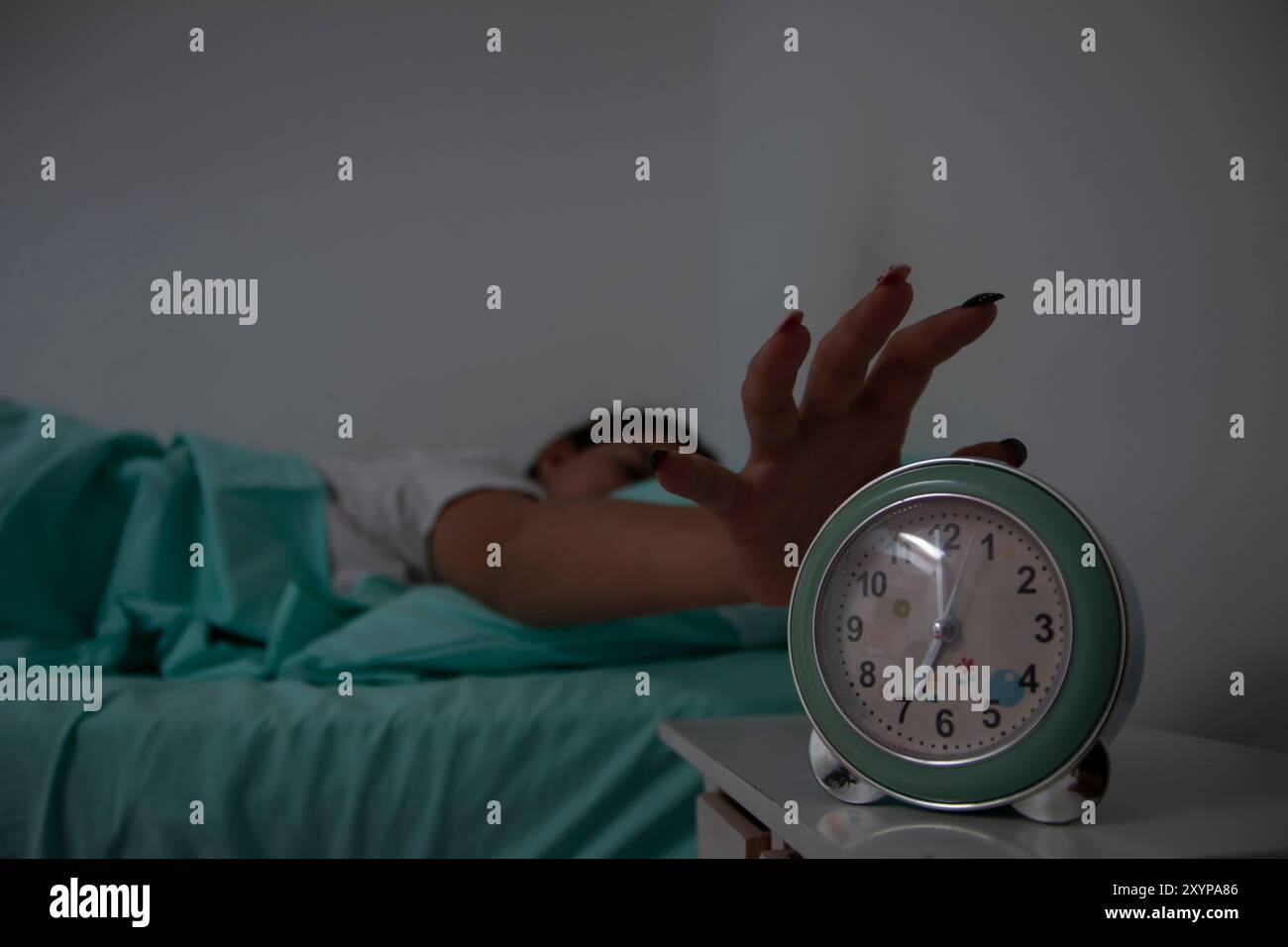 Waking up of an asleep girl stopping alarm clock on the bed in the ...