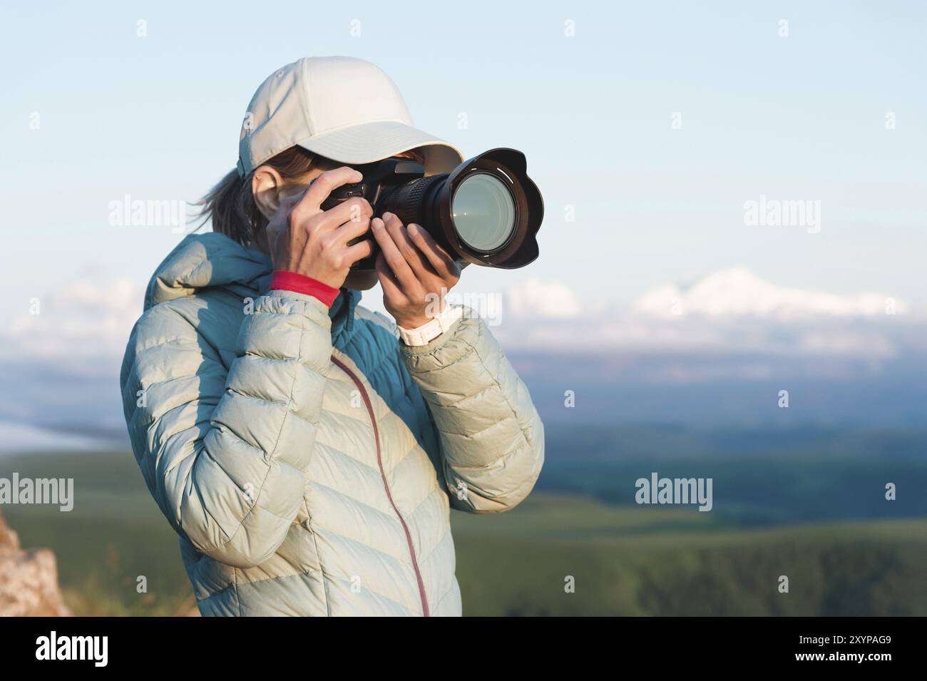 Portrait of a girl photographer in a cap on nature photographing on her ...
