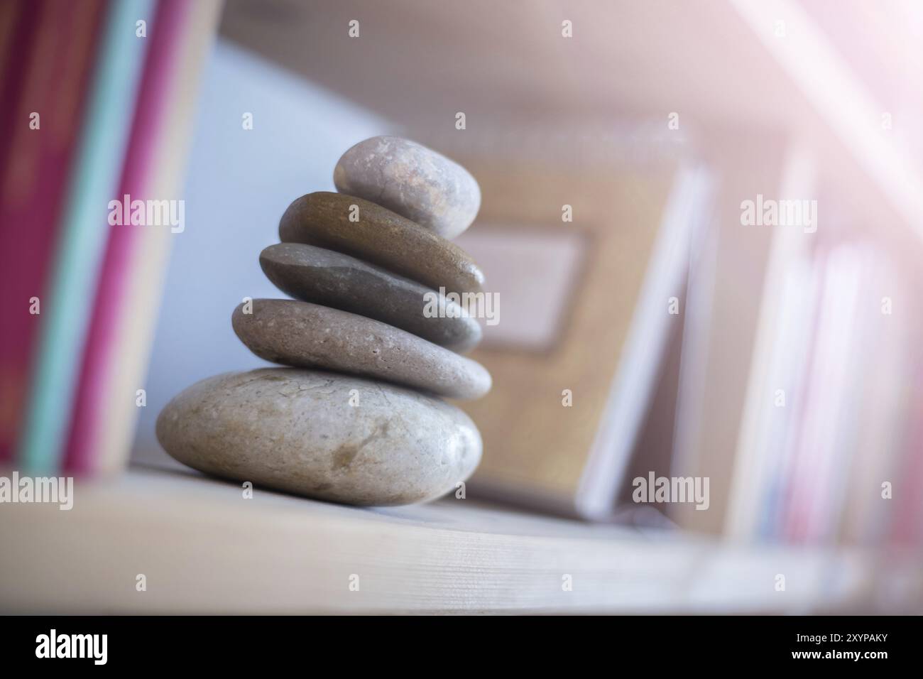 Feng Shui: Stone cairn at home in a book shelf, blurry books in ...