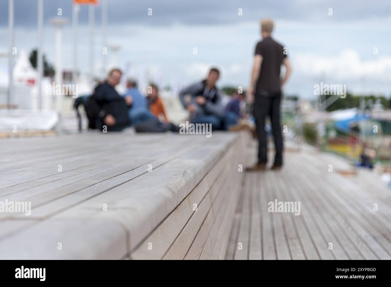 A group of people sitting on wooden benches on the beach in Travemuende ...