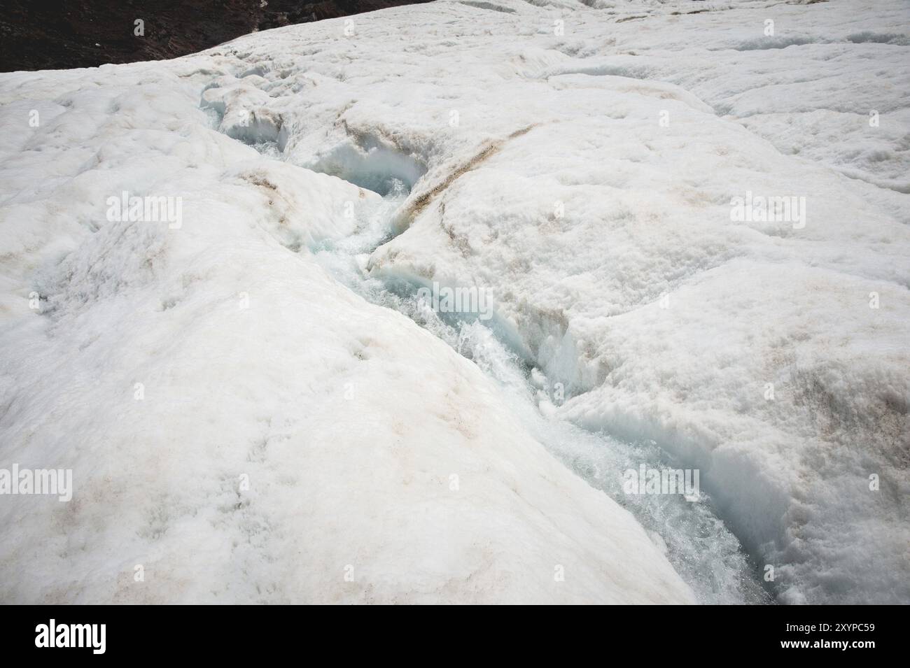 A close-up of a meltwater stream flows along a slope through a glacier ...