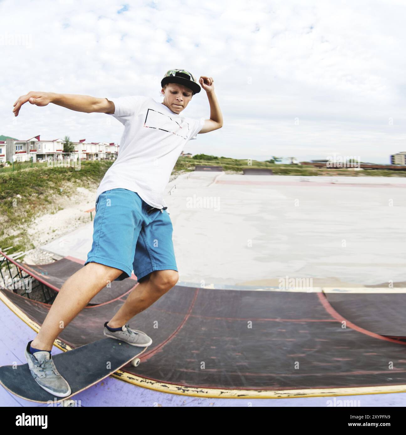 Teen skater hang up over a ramp on a skateboard in a skate park. Wide ...