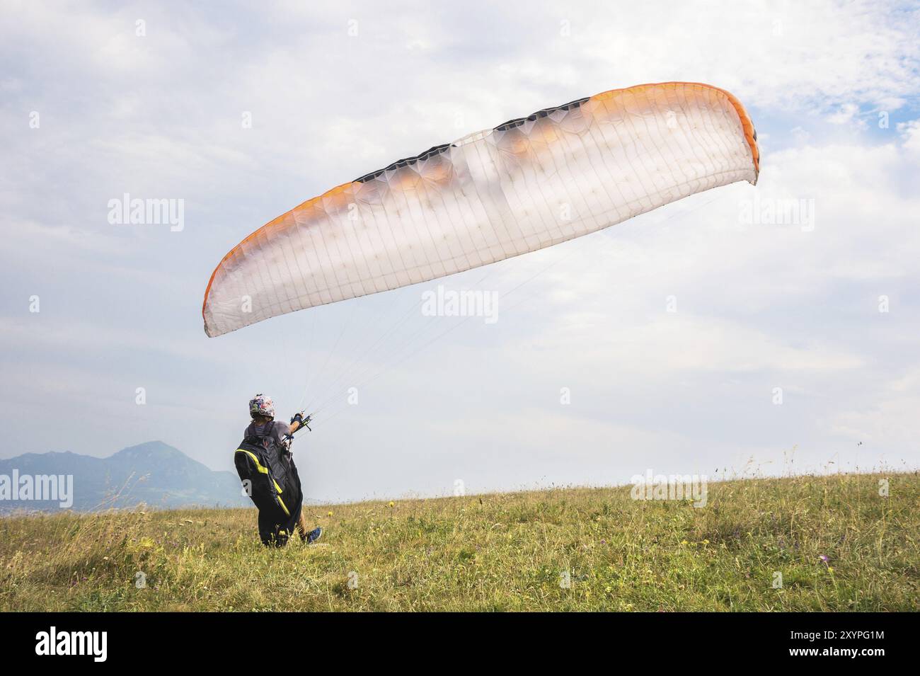 The paraglider opens his parachute before taking off from the mountain ...