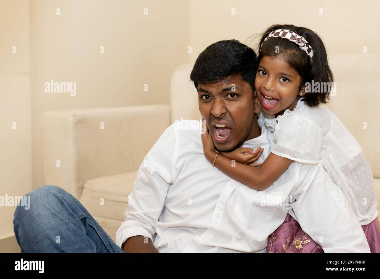 A father and his young daughter share a moment of joy as she playfully ...