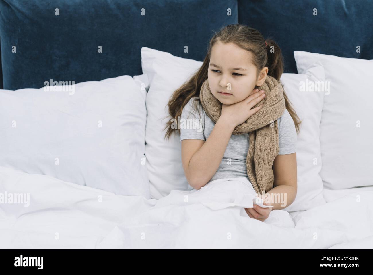 Sick girl sitting bed with scarf around her neck suffering from sore ...