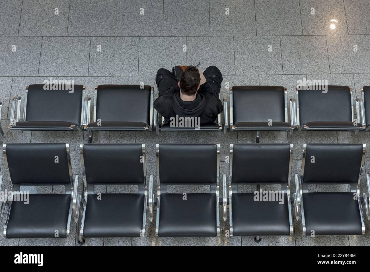 A single man sits in the centre of a chair in a double row. Top view ...