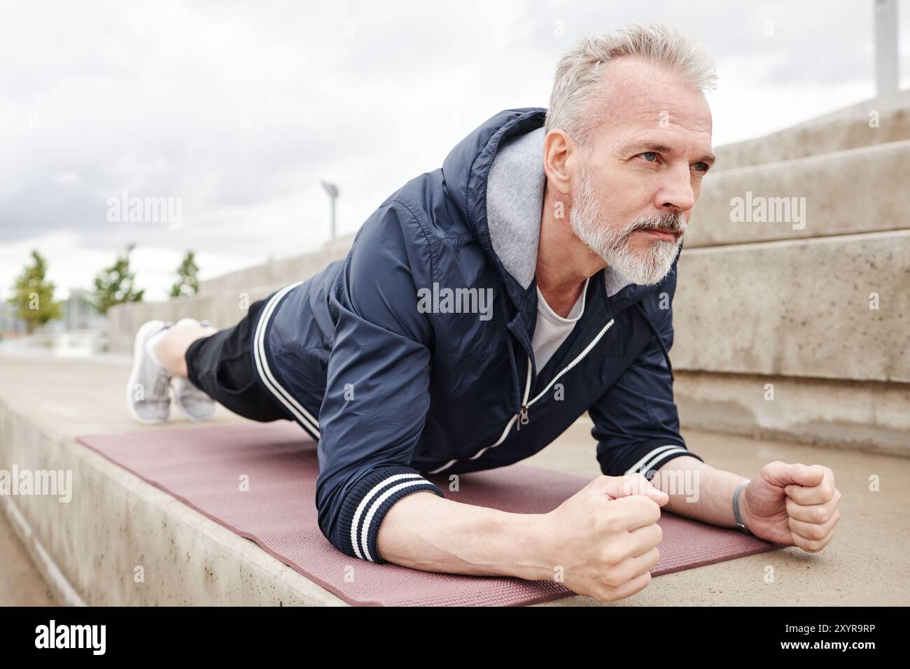 Sporty determined elderly man holding plank position on yoga mat ...