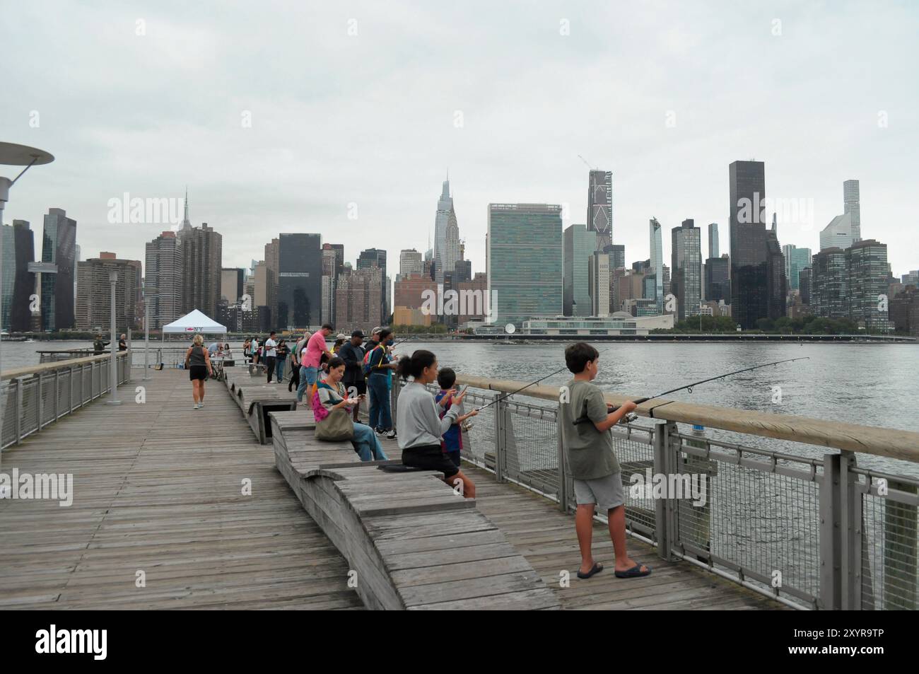 People fish at the docks by the East River in Long Island City, Queens ...