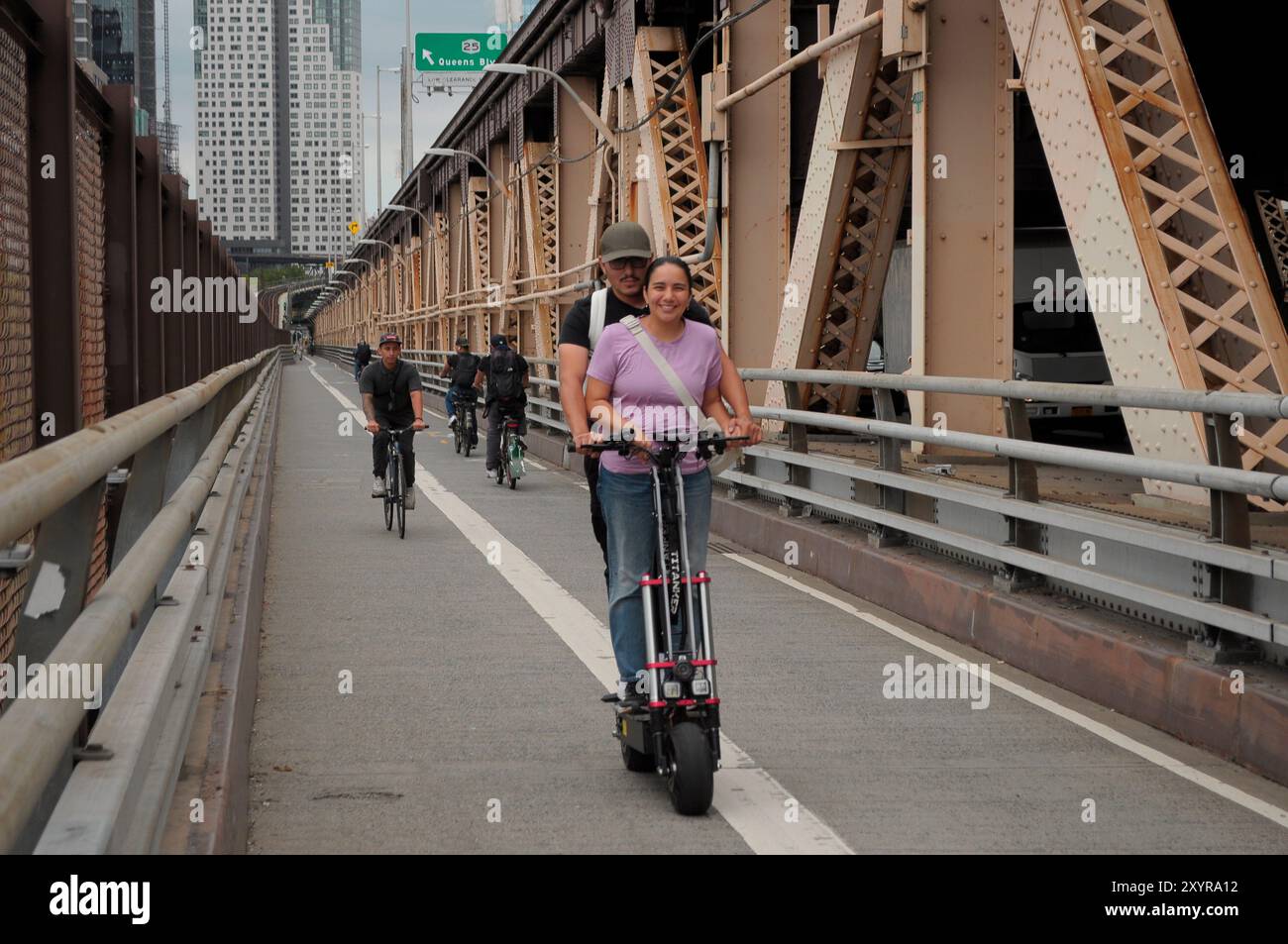 Two people ride a scooter across the Queensboro Bridge in New York City ...