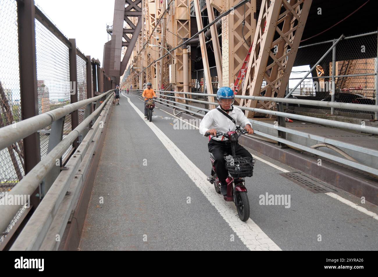 A man rides a scooter across the Queensboro Bridge in New York City ...