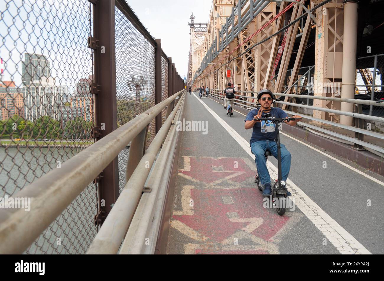 A man rides a scooter across the Queensboro Bridge in New York City ...