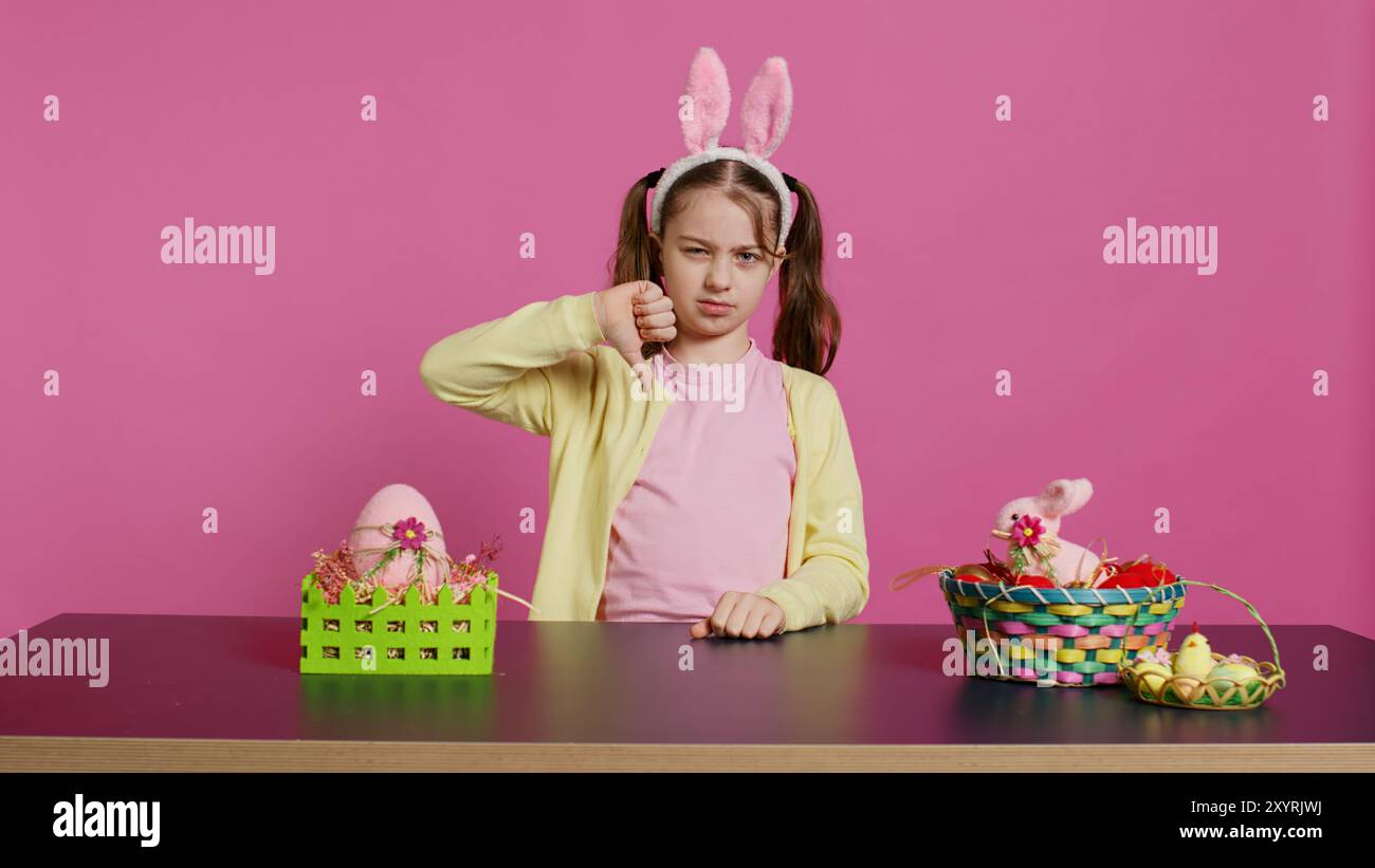 Displeased unhappy child giving thumbs down in studio, expressing her ...