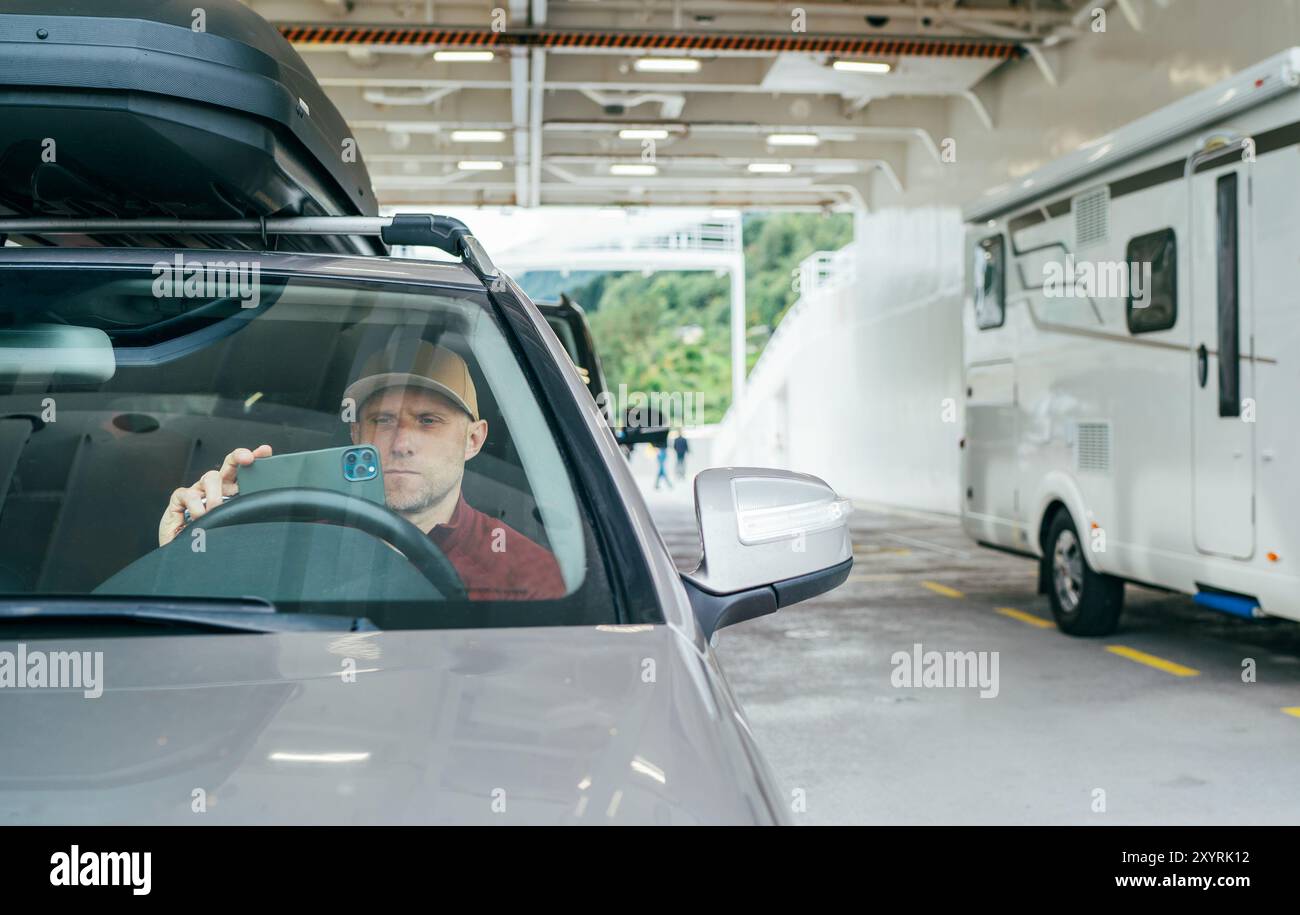 Serious man sits in car aboard Norwegian ferry, surrounded by other ...