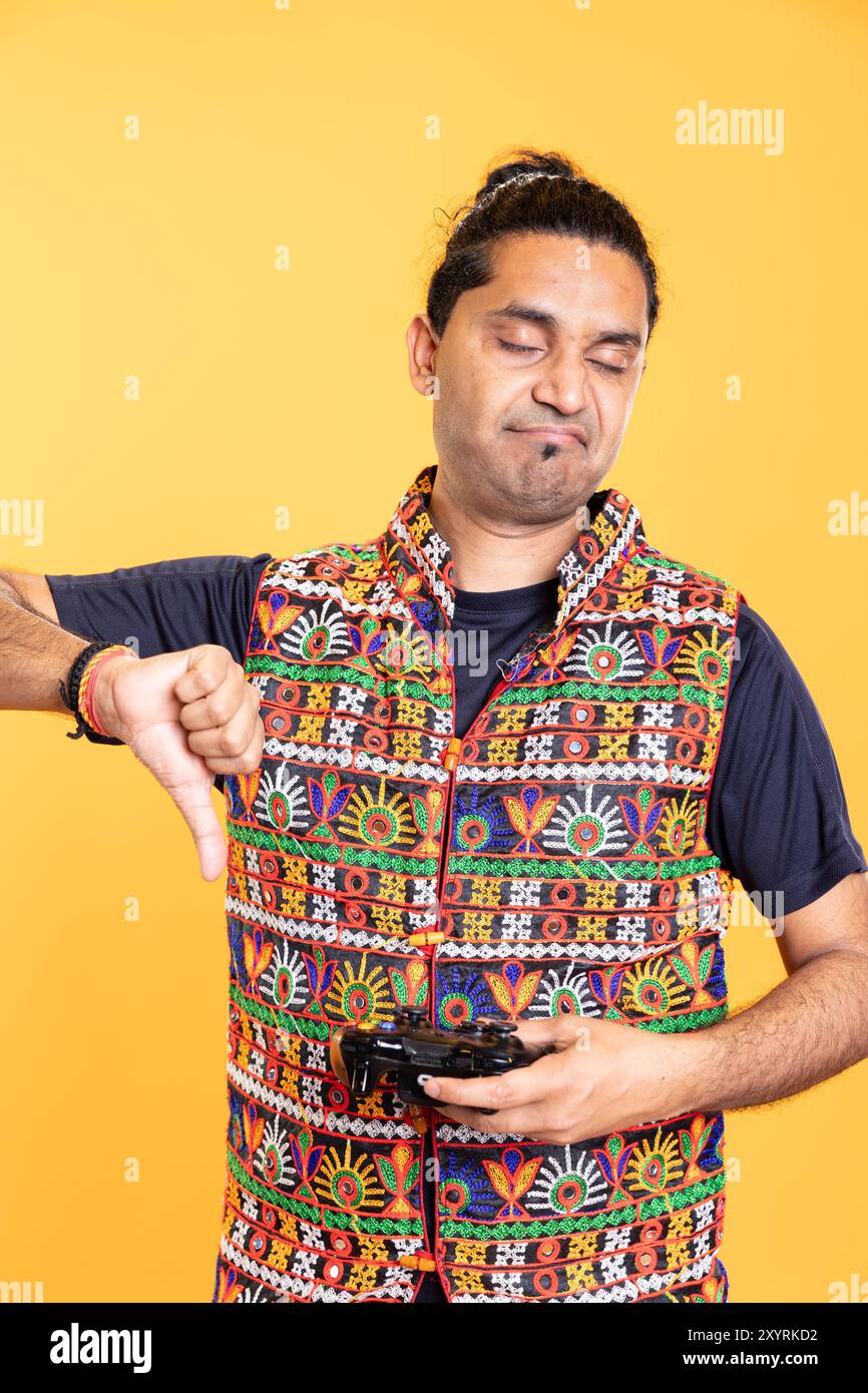 Portrait of annoyed man showing thumbs down sign holding gamepad ...