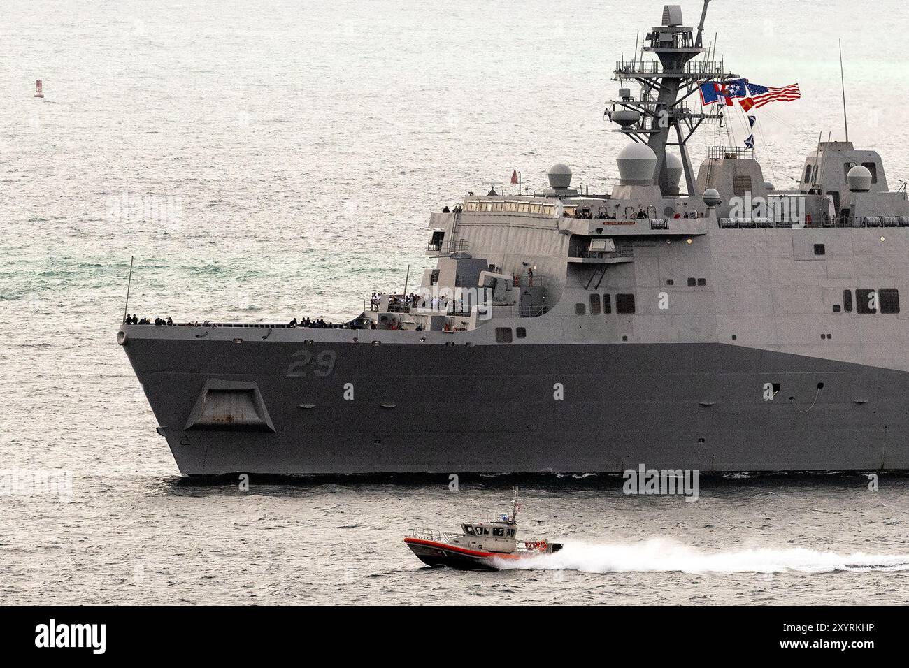 A U.S. Coast Guard patrol boat escorts the USS Richard M. McCool Jr ...