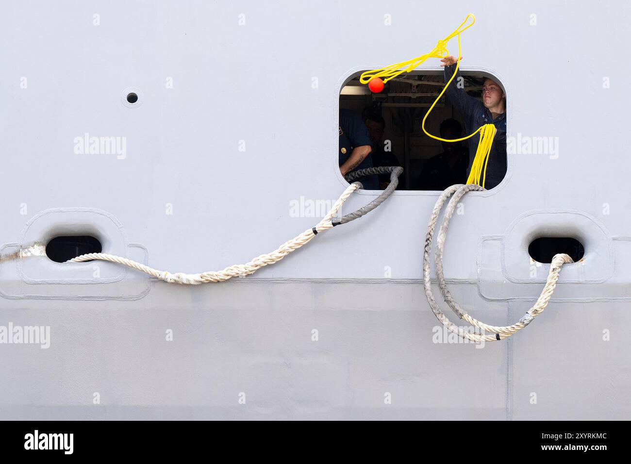 A Sailor aboard the USS Richard M. McCool Jr. (LPD 29) throws a line to ...