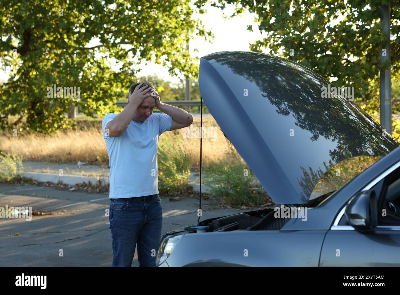 Stressed man looking under hood of broken car outdoors Stock Photo - Alamy
