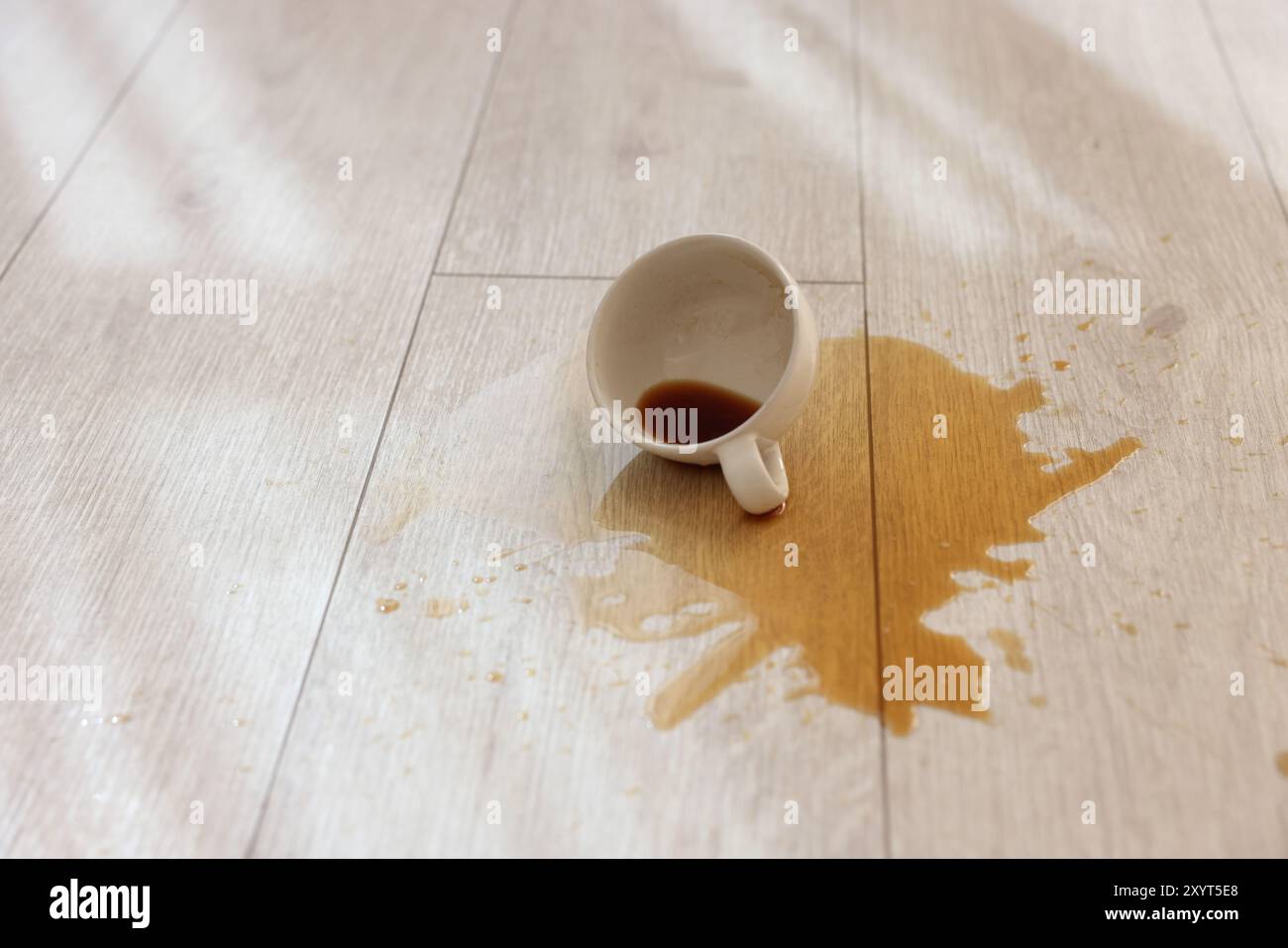 Cup with spilled drink on wooden floor Stock Photo - Alamy