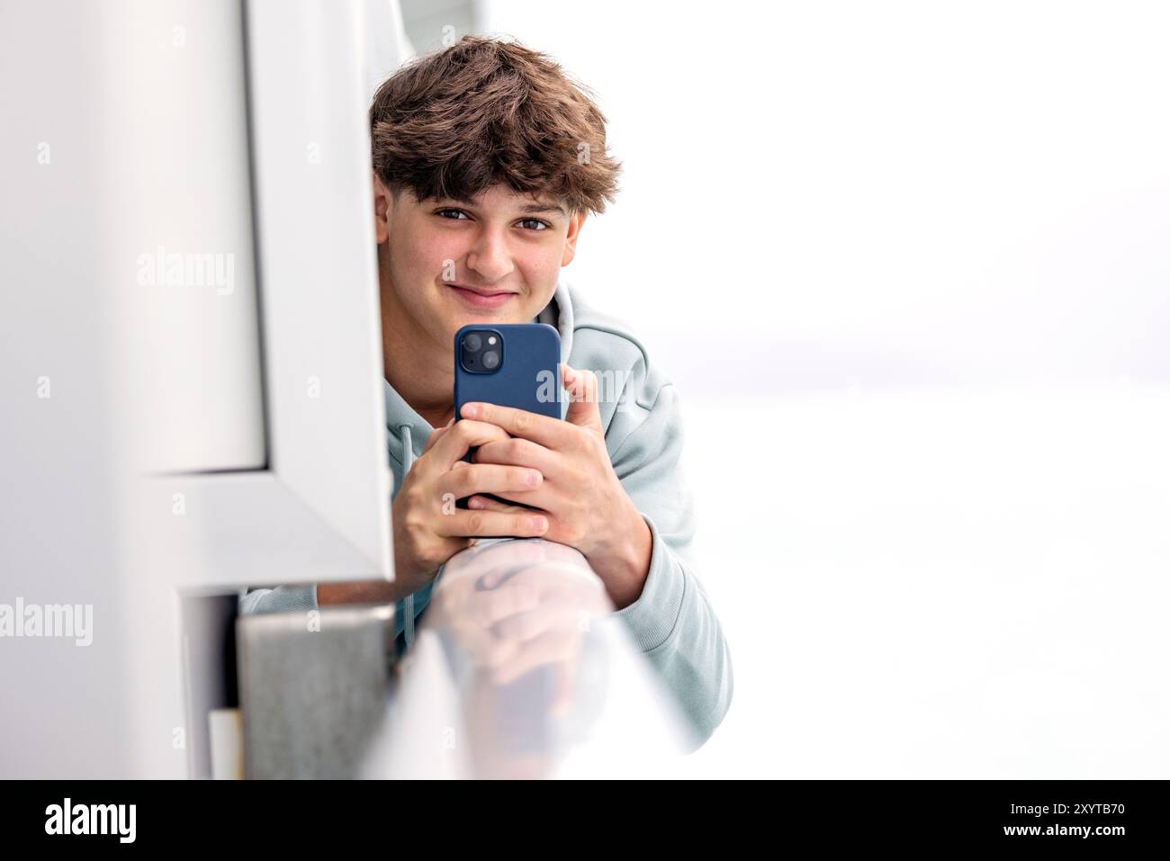 Picture of teenage boy holding cell phone and looking at camera ...