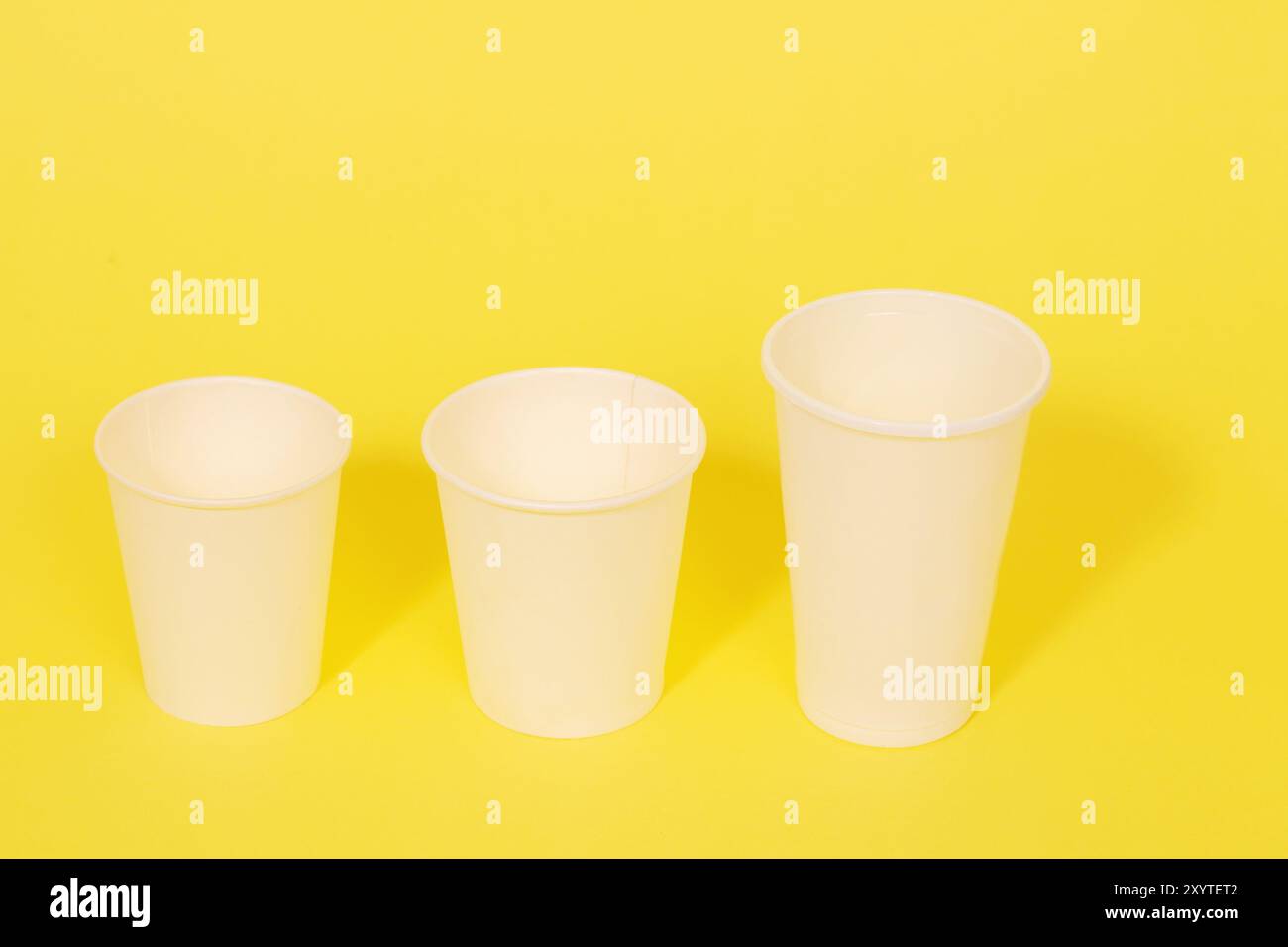Three white plastic disposable cups on a yellow paper background Stock ...