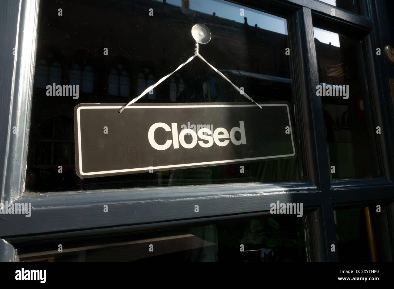 Closed sign in the glass door of a small business indicating economic ...