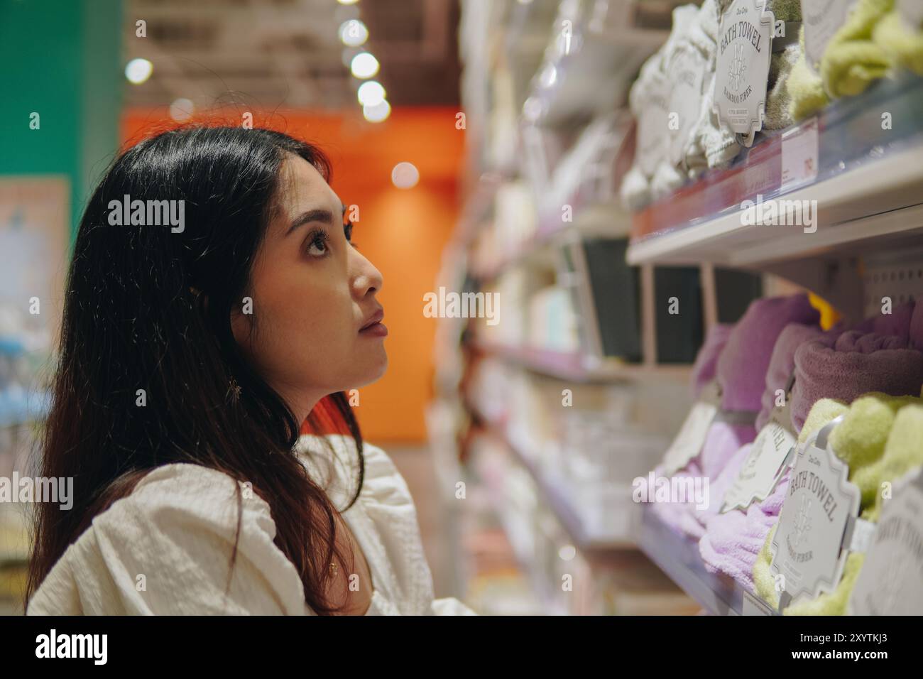 Cute young Asian woman is shopping in a department store and looking at ...