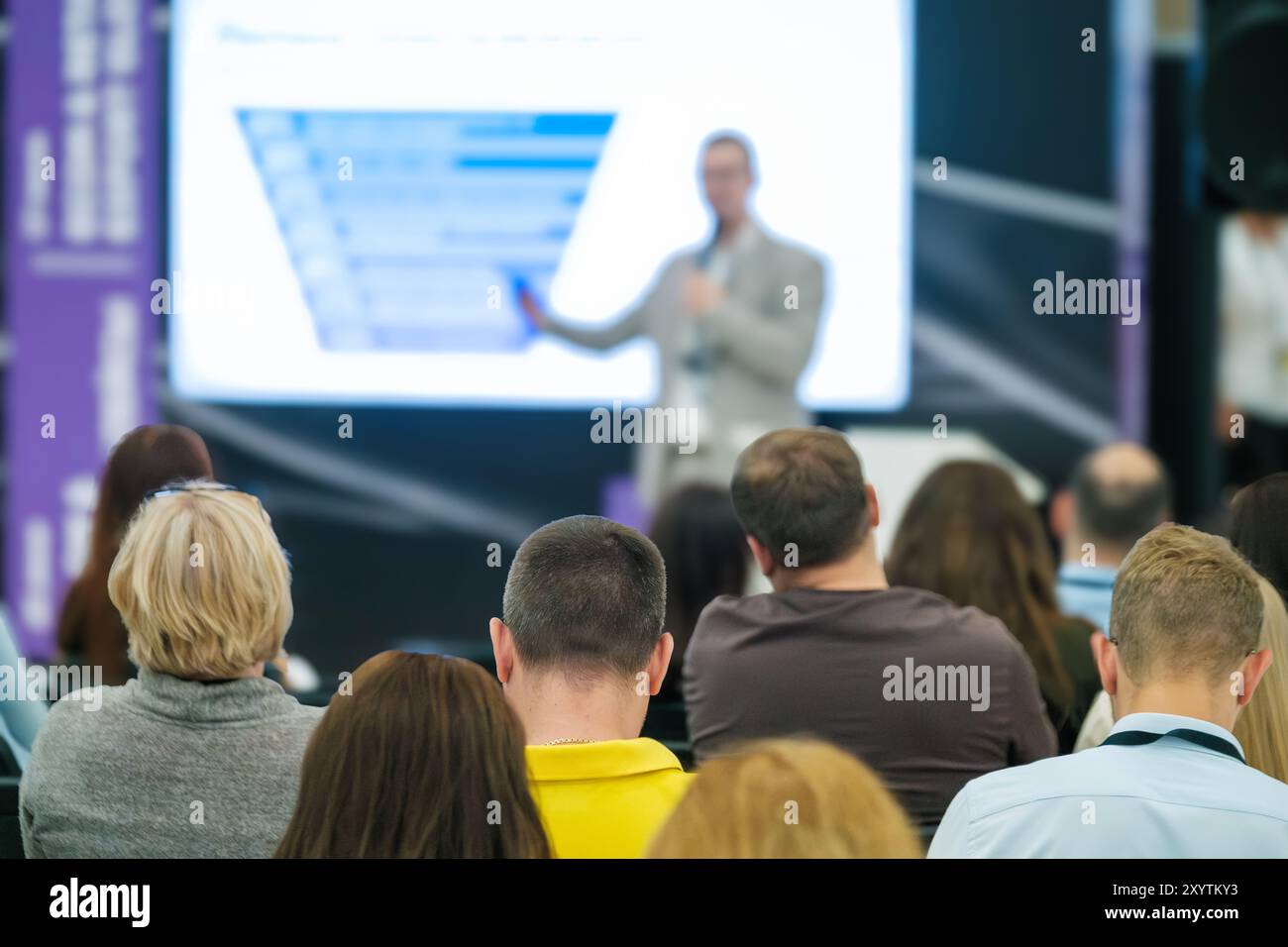 Audience attending a business seminar with a speaker presenting a ...