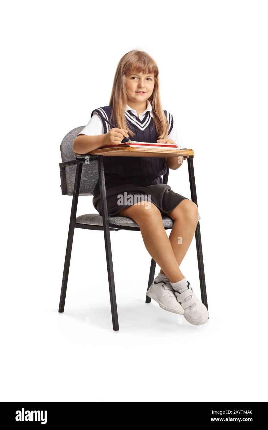 Girl in a school uniform sitting and writing isolated on white ...