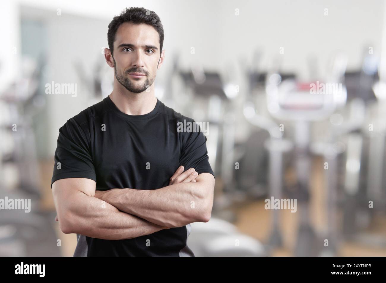 Personal trainer with is arms crossed, in a gym Stock Photo - Alamy