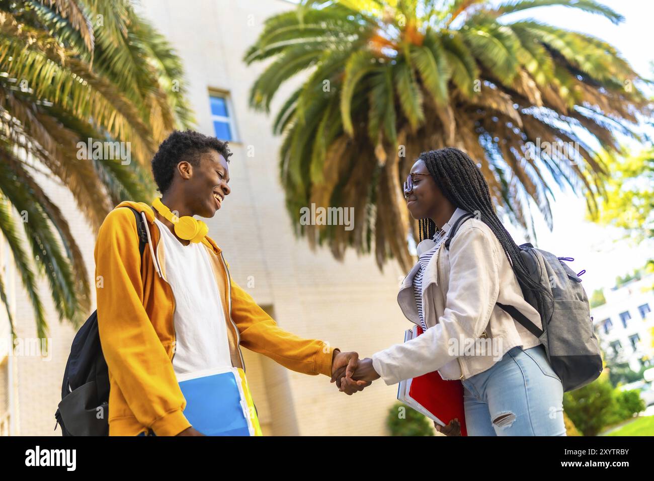 Side view of two young cool african university students shaking hands ...