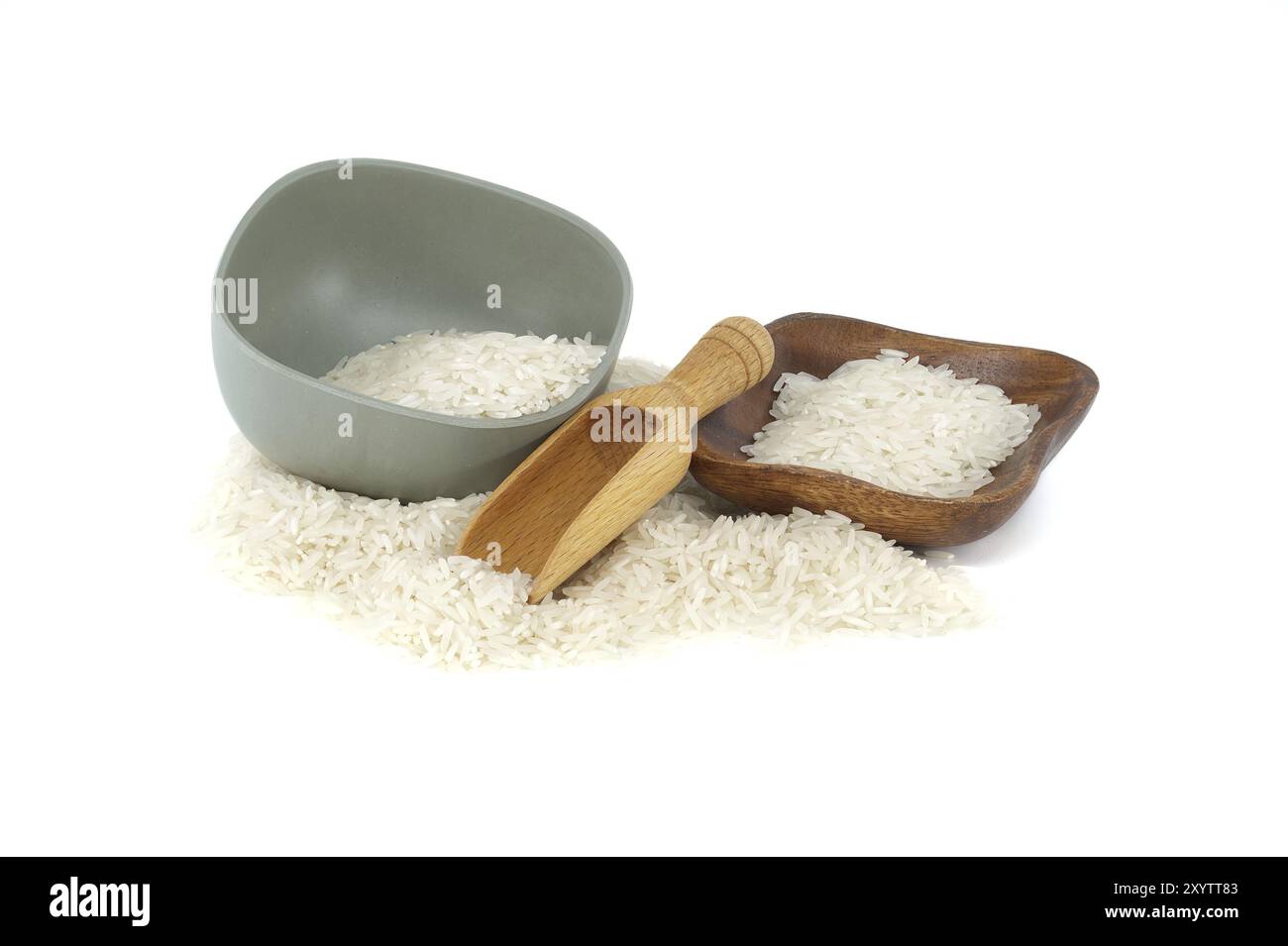 Dry long-grain rice in wooden bowls and wooden scoop isolated on white ...