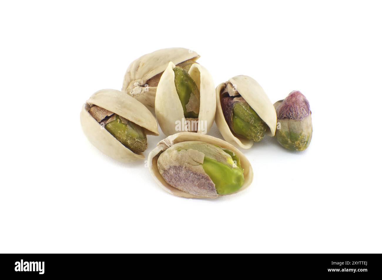 Pistachios are randomly spread across the white surface, some ...