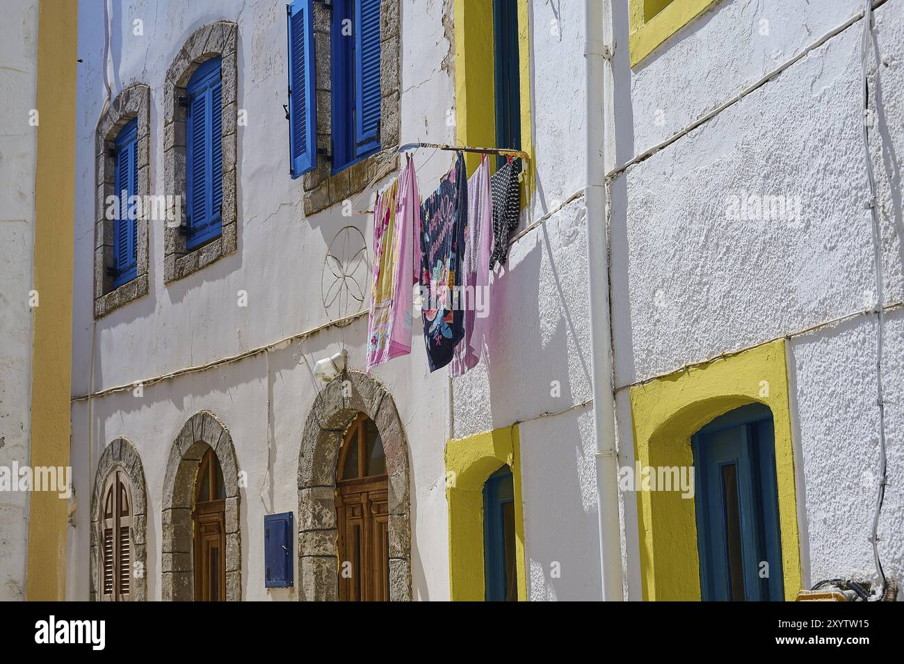 Colourful laundry hanging between houses with blue and yellow shutters ...