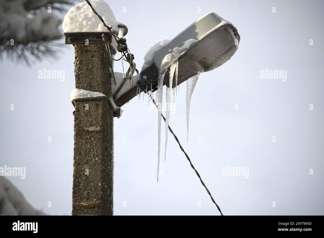 Close-up of an electrical post blanketed in snow with icicles adorning ...