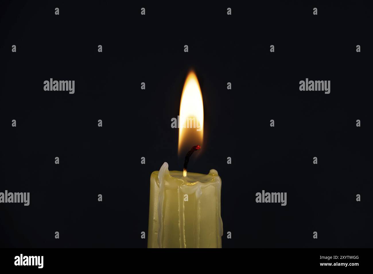 Burning yellow wax candle contrasting with the dark background, candle ...