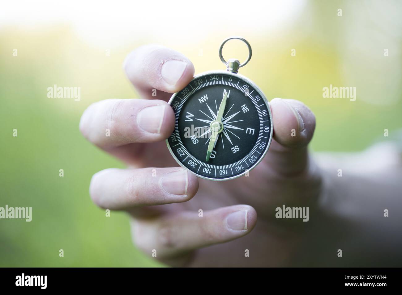 Young man on an adventure is holding a compass in his hand for finding ...