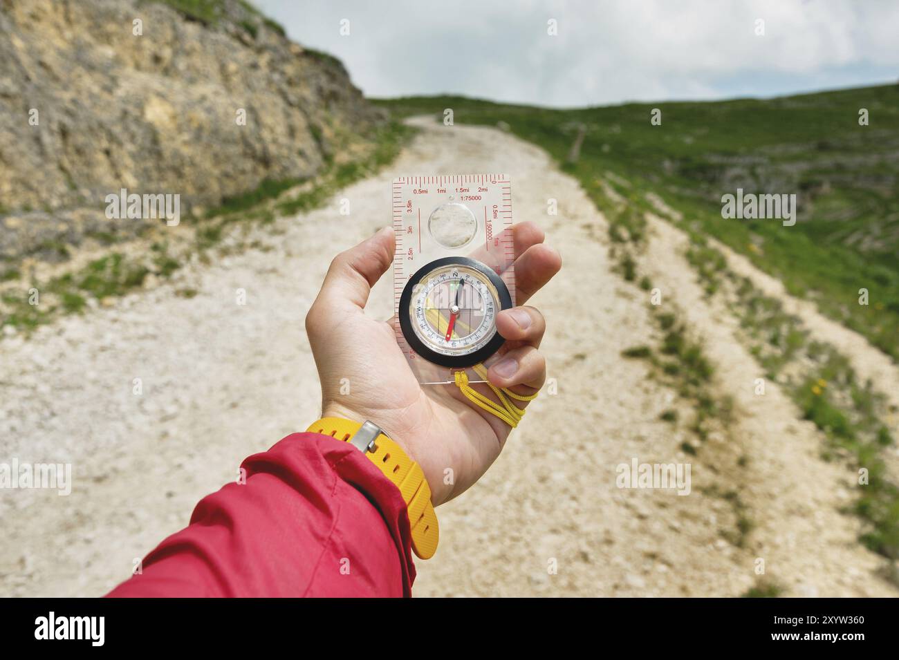Male hand is holding a magnetic compass on the background of hills and ...