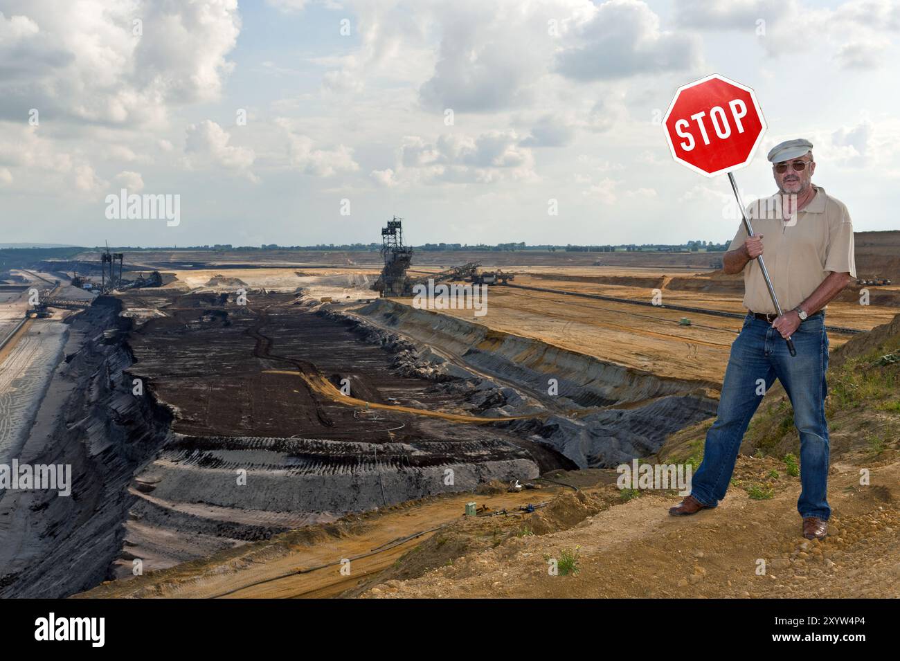 Man standing at the edge of the open-cast mine holding up a STOP sign ...
