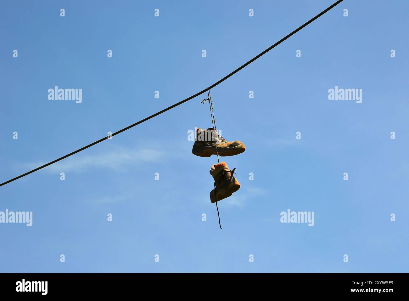 Shoes hanging from an overhead line at a great height Stock Photo - Alamy
