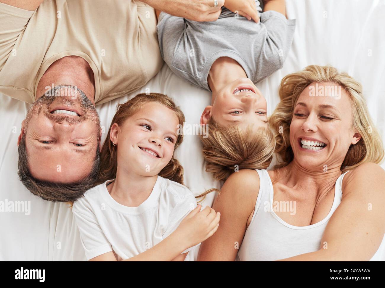 Family, happy and relax on bed in home with playing, resting and ...