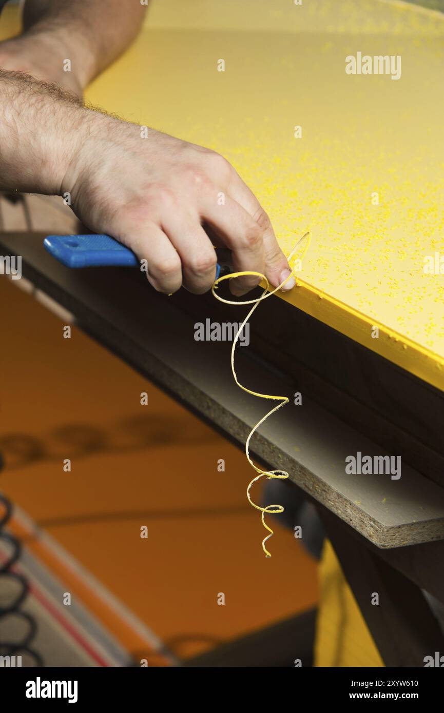 A professional carpenter processes the plastic edges of the countertop ...