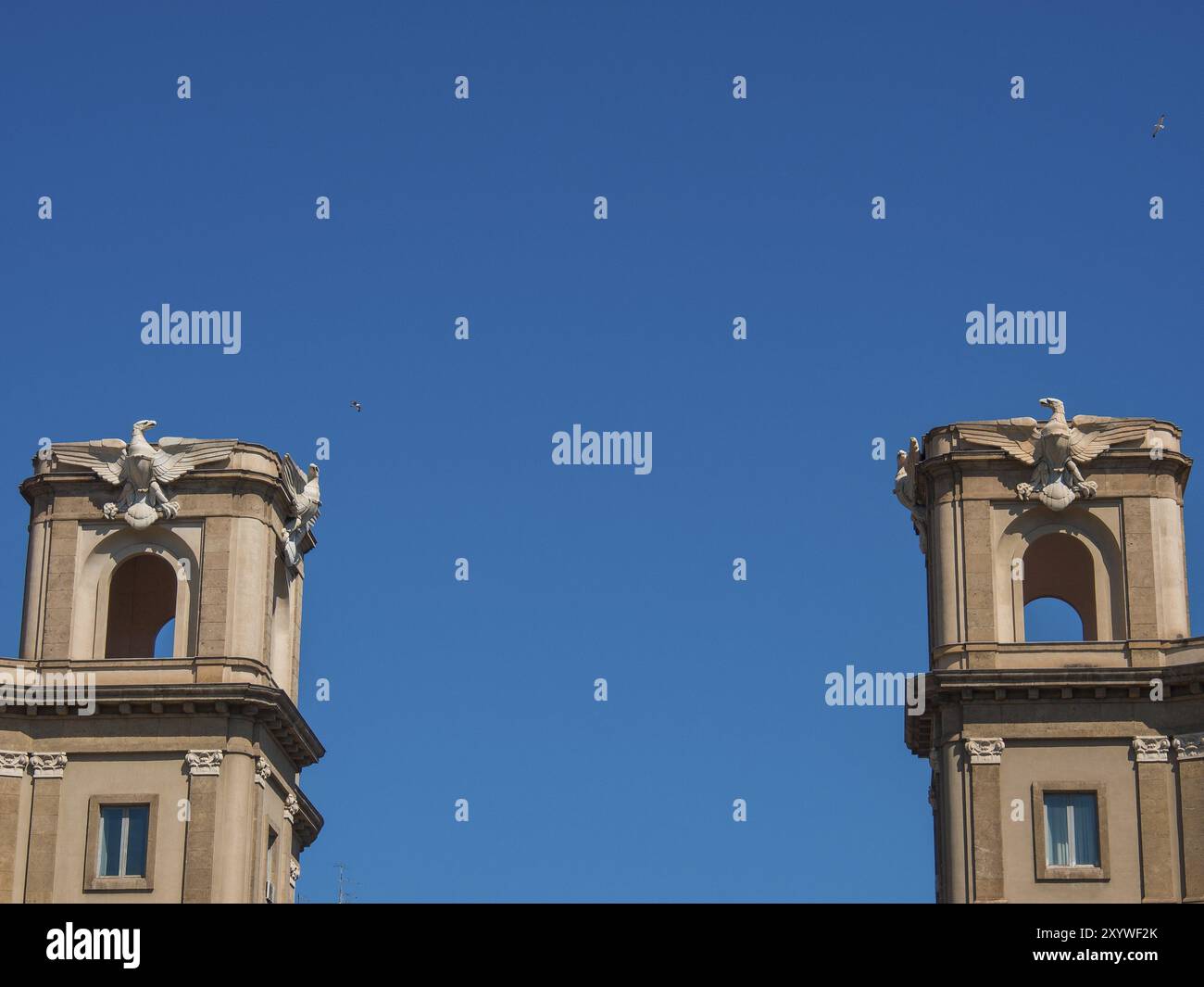 Two towers of a classical building with eagle sculptures in front of a ...